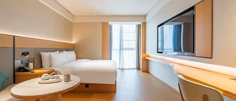 Quarto de hotel moderno com uma cama, mesa de cabeceira e escrivaninha com cadeira.
