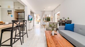 Uma cozinha moderna com área de refeições, um sofá cinza e uma mesa de centro de madeira.