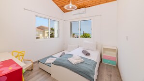 Quarto com teto de madeira, duas camas, uma escrivaninha e uma cadeira.
