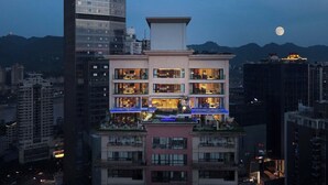 Um hotel com vários andares, varandas e um terraço no telhado.