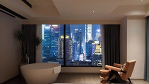 Quarto moderno com grande janela e vista para a cidade, banheira e área de estar.