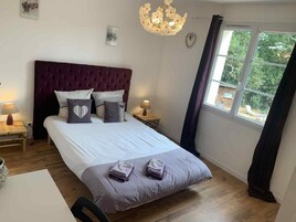 Quarto com uma cama grande, duas mesas de cabeceira, um candelabro e uma janela com cortinas.