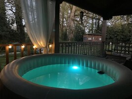 Uma banheira de hidromassagem sob uma área coberta, com deck de madeira e luzes de fada.