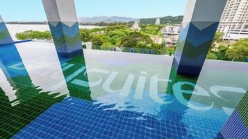 Piscina com vista para um horizonte urbano e montanhas ao fundo.