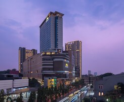 Um hotel moderno com uma torre de canto imponente, vários andares e fachada bem iluminada.