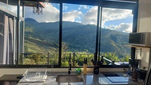 Cozinha com uma grande janela com vista para uma paisagem montanhosa.