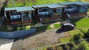 Uma casa moderna com paredes de vidro, garagem coberta e área de estar externa coberta.
