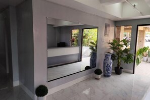 Interior moderno com um espelho grande, plantas em vasos e piso de mármore.