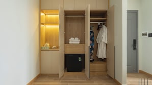 Um closet amplo com portas de madeira, uma pequena geladeira preta e toalhas dobradas com cuidado.