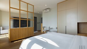 Quarto de hotel moderno com uma cama grande, um painel de madeira, uma mesinha e uma cadeira.