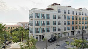 Um hotel com vários andares, pátio central, janelas amplas e uma combinação de varandas e entradas no nível do solo.