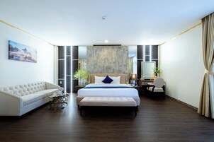 Quarto de hotel moderno com uma cama grande, um sofá, uma escrivaninha e uma cadeira.