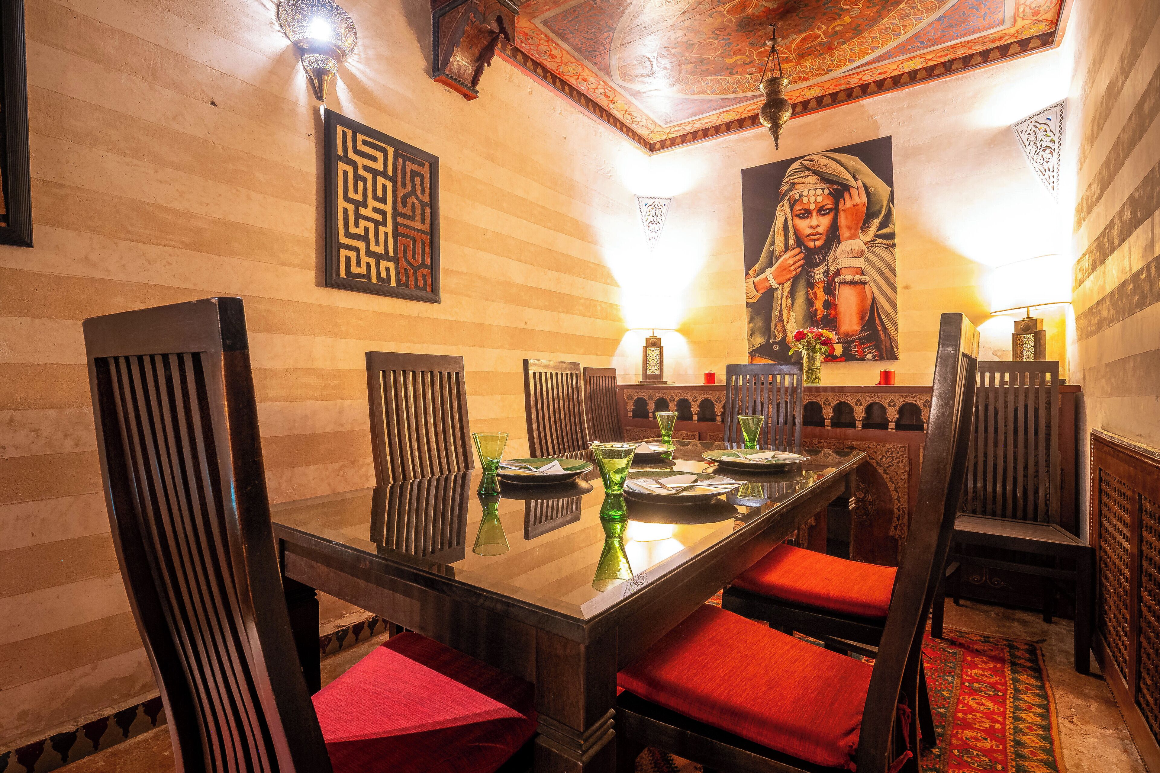 Uma sala de jantar com uma mesa comprida, cadeiras e um papel de parede estampado.