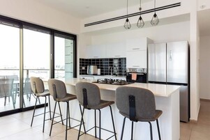 Uma cozinha moderna com ilha central, banquetas e uma grande janela.