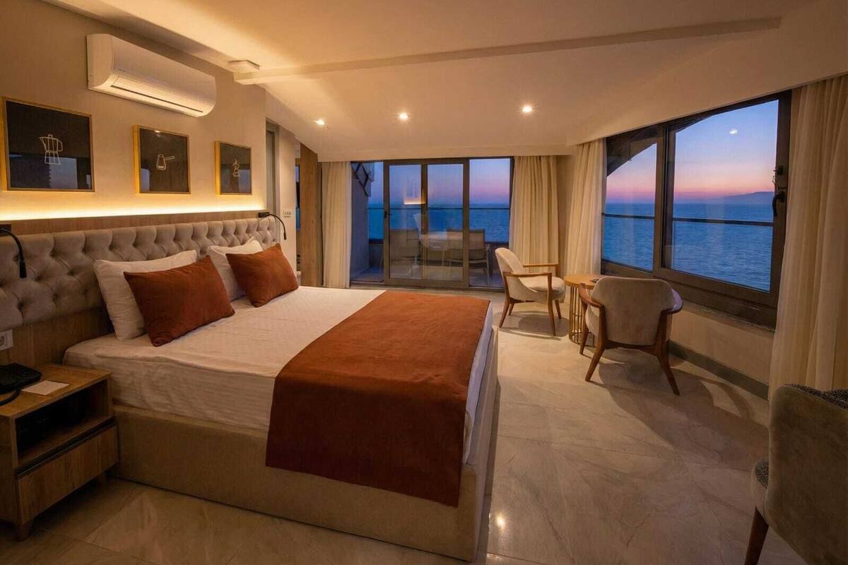 Quarto de hotel com uma cama grande, uma escrivaninha e vista para o mar.