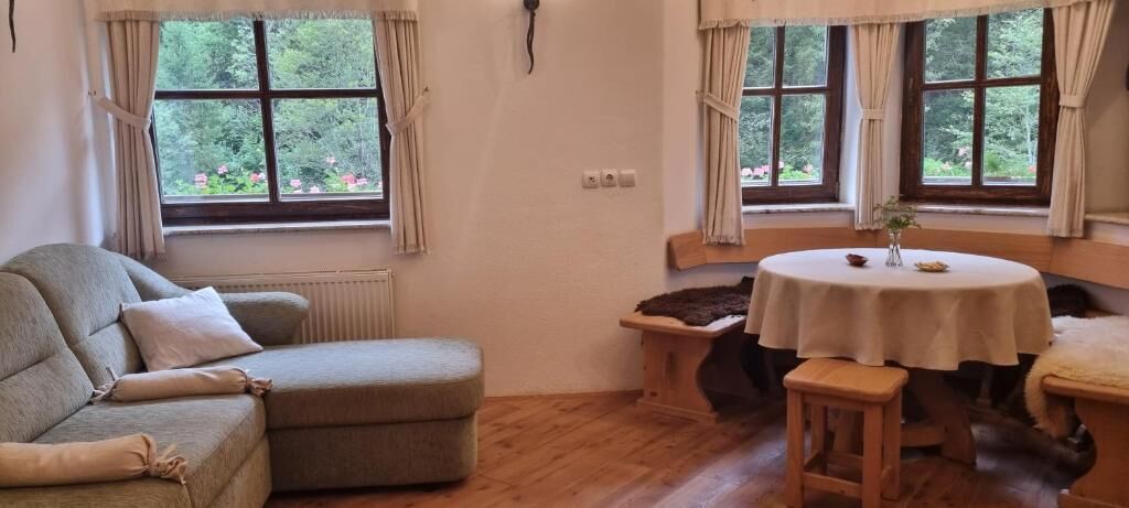 Um quarto aconchegante com sofá, mesa redonda e janela com cortinas.