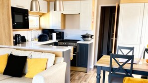 Um espaço compacto com cozinha compacta, área de refeições e sofá com almofadas.
