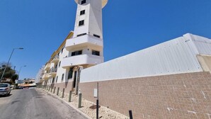 Um edifício com uma torre imponente, uma estrada pavimentada e um céu azul límpido.