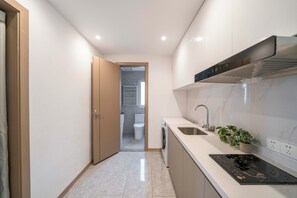Uma cozinha moderna com fogão embutido, pia e vista para o banheiro adjacente.