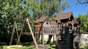 Uma casinha de madeira com balanço e uma mesa pequena.
