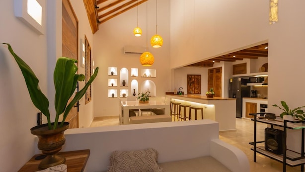 Um interior moderno com área de refeições, cozinha e espaço para sentar.