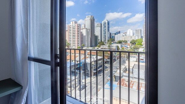 Vista da janela com guarda-corrimão de metal, mostrando um horizonte urbano com arranha-céus e uma rua movimentada abaixo.