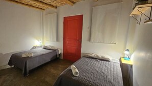 Quarto com duas camas, uma porta vermelha e uma cadeira vermelha.