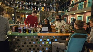 Um bar com diversos tipos de garrafas e um bartender atendendo clientes.