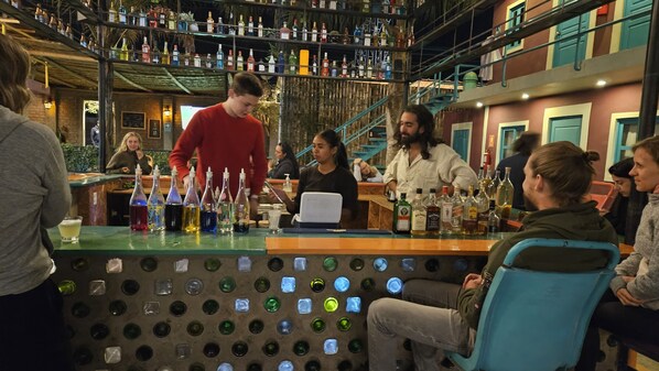 Um bar com diversos tipos de garrafas e um bartender atendendo clientes.
