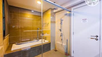 Casa de banho com chuveiro em cabine de vidro, banheira e porta branca com um aviso.