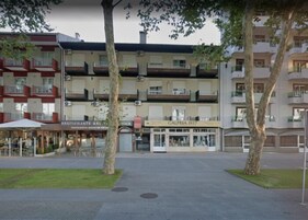 Um hotel com vários andares, varandas, um restaurante e uma loja.