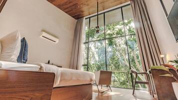 Quarto moderno com teto de madeira, uma janela grande com cortinas, cama, cadeira e escrivaninha.
