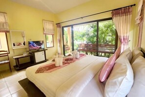 Quarto com cama, escrivaninha, televisão e janela com cortinas.