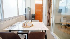 Uma área de refeições com uma mesa de mármore, cadeiras, um frigorífico e uma porta de madeira.