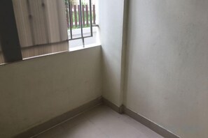 Quarto nos cantos com janela, porta e chão de azulejos.