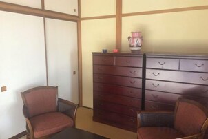 Quarto com um grande aparador de madeira, duas cadeiras e uma porta tradicional japonesa de correr.