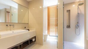 Uma casa de banho moderna com um espelho grande, uma sanita e um chuveiro, e uma pia dupla.