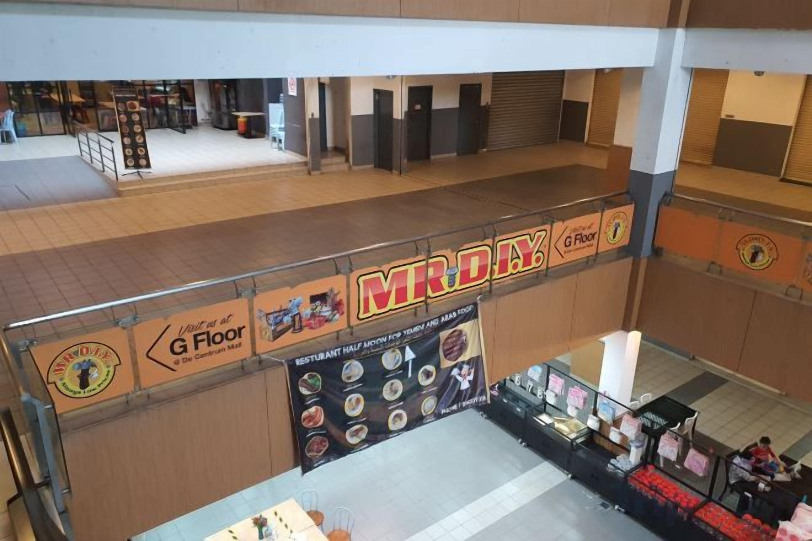 Espaço interno com um restaurante identificado como G Floor, uma placa Mr. Day e uma vitrine de comida.
