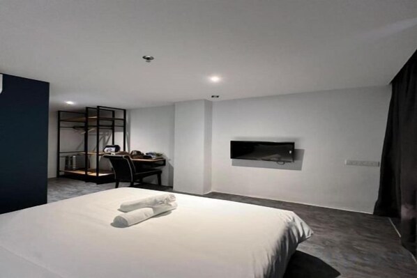 Quarto de hotel moderno com uma cama grande, uma escrivaninha e uma TV fixada na parede.