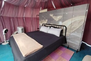 Um quarto com uma cama, um ventilador de cabeceira, um aquecedor e um guarda-roupa grande.
