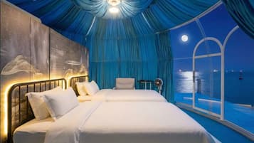 Quarto com duas camas, uma janela grande e vista para o mar.