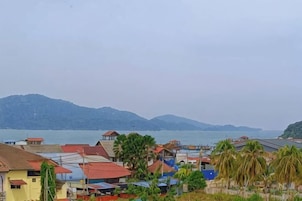 Uma cidade costeira com casas, um corpo d'água e colinas ao fundo.