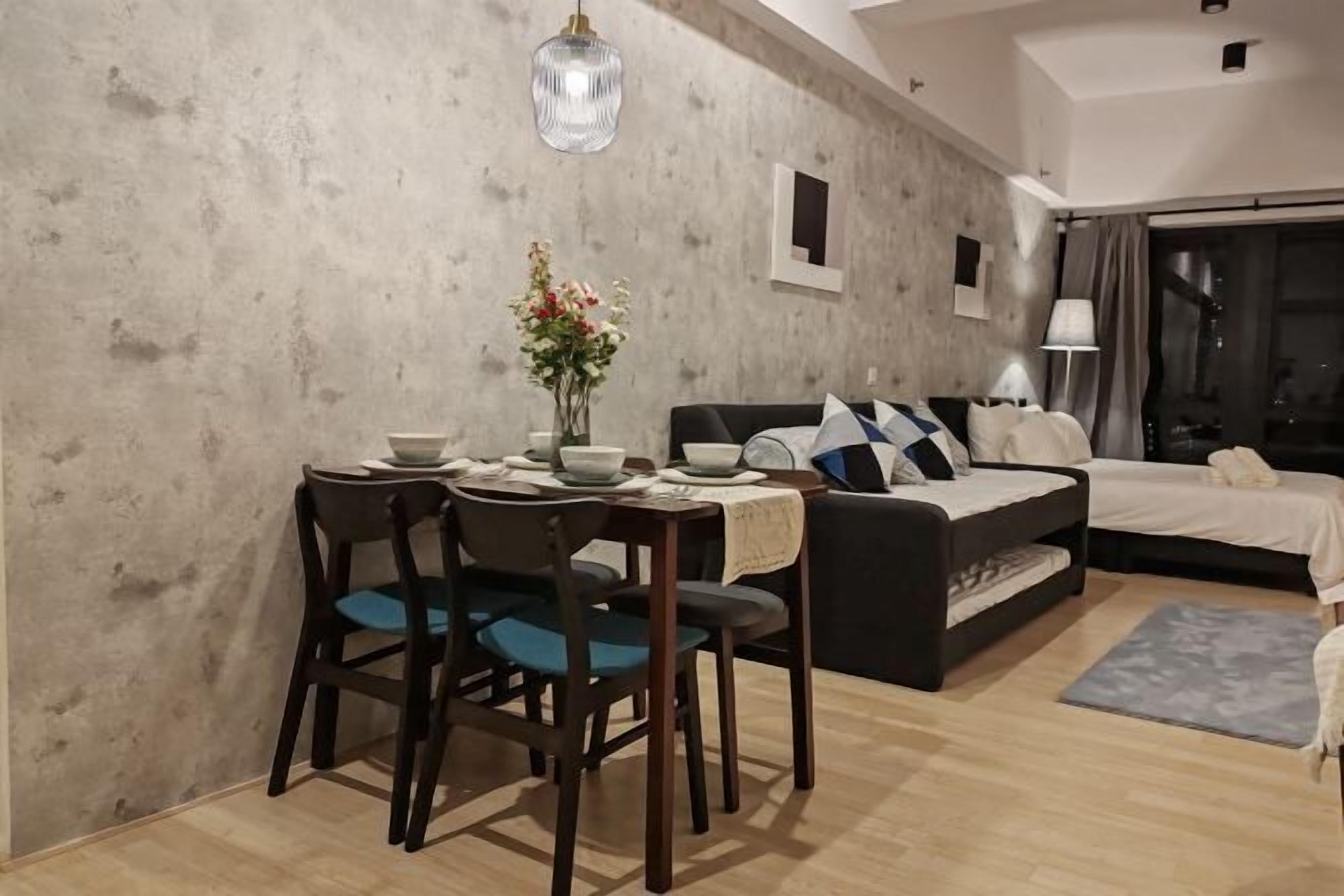 Uma sala de estar moderna com área de jantar, apresentando um sofá, uma mesa de jantar com cadeiras e um vaso com flores.