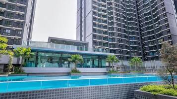 Um edifício residencial alto com piscina, arquitetura moderna e áreas verdes ao redor.