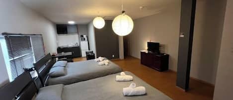 Quarto de hotel com duas camas, televisão, escrivaninha e guarda-roupa.