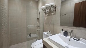 Uma casa de banho moderna com cabine de duche em vidro, lavatório branco com balneário e armário de madeira.