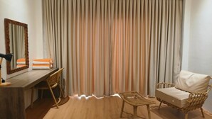 Um quarto com escrivaninha, cadeira e sofá.
