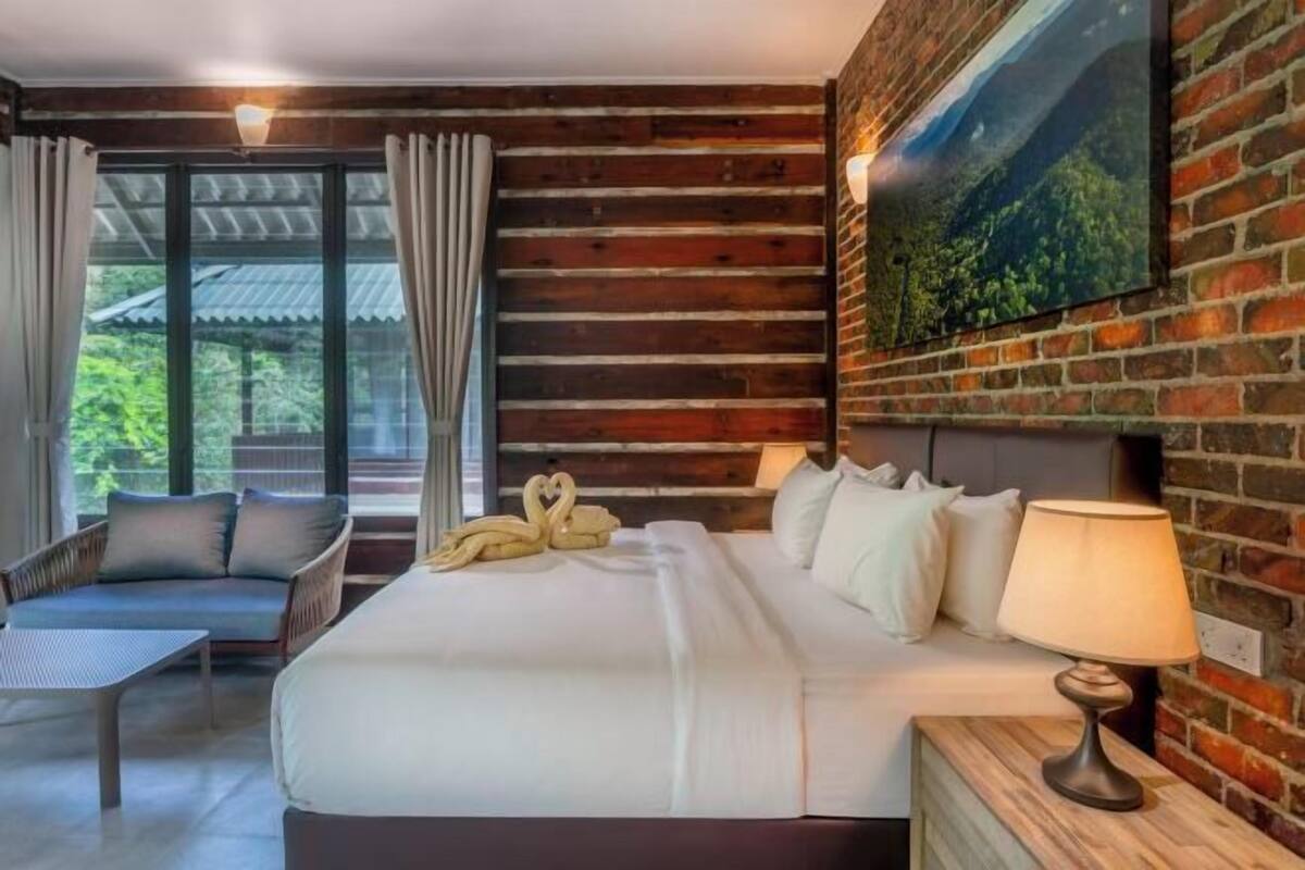 Quarto com cama grande, sofá, mesa e luminária na parede.