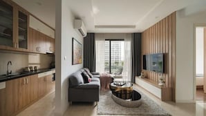 Um apartamento moderno com cozinha, sala de estar e televisão fixada na parede.