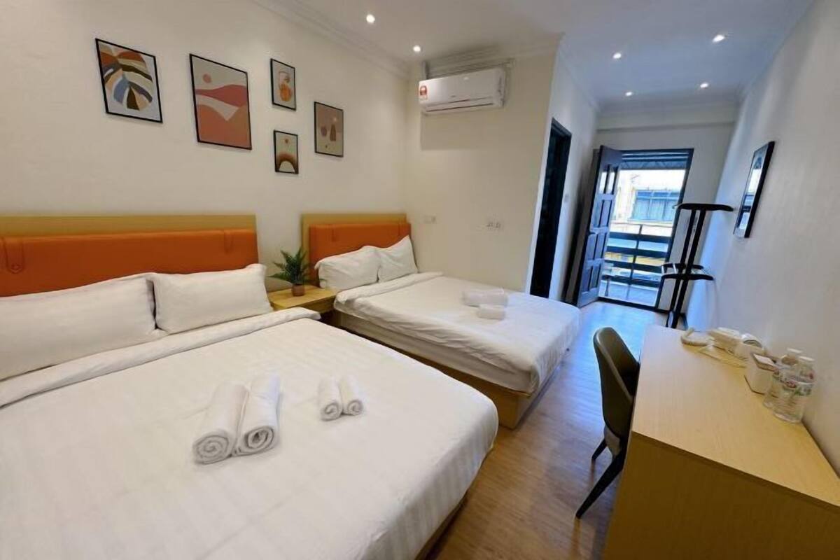 Quarto de hotel com duas camas, uma escrivaninha e uma cadeira.